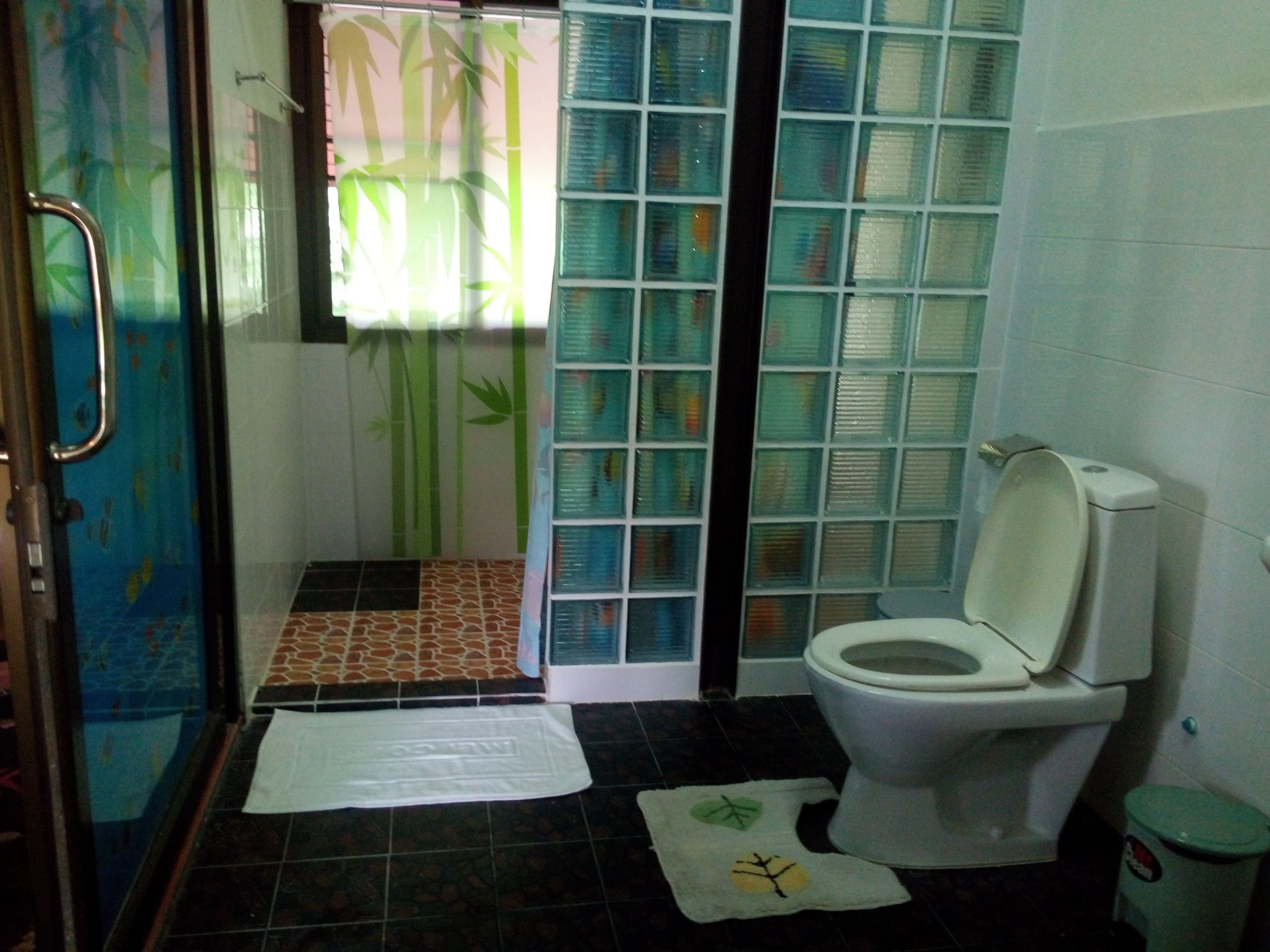 Casa de banho com sanita, zona de duche e chão em mosaico.