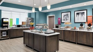 Um café moderno com ilha central, área de estar e diversos pontos de comida e bebida.