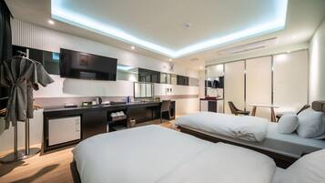Quarto de hotel moderno com duas camas, uma escrivaninha, uma televisão e um guarda-roupa.