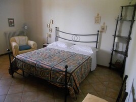 Um quarto com uma cama, uma cadeira, um radiador e uma prateleira.