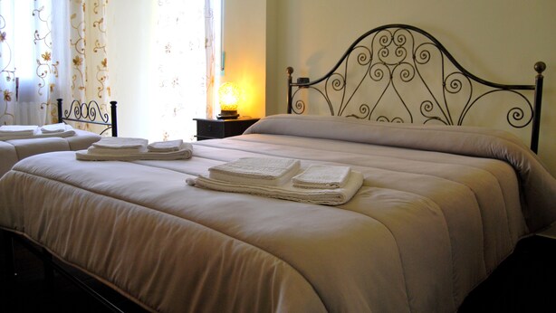 Quarto de hotel com uma cama, uma mesa de cabeceira e uma luminária.