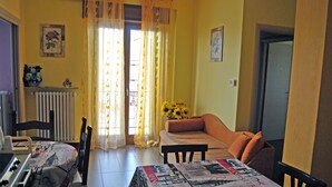 Uma área de refeições com mesa posta para dois, um sofá e um radiador.