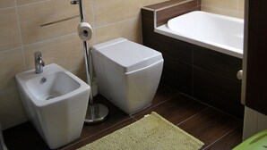 Uma casa de banho com bidé, sanita e banheira.