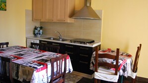 Cozinha com armários de madeira, coifa em aço inoxidável, pia e mesa de jantar com cadeiras.