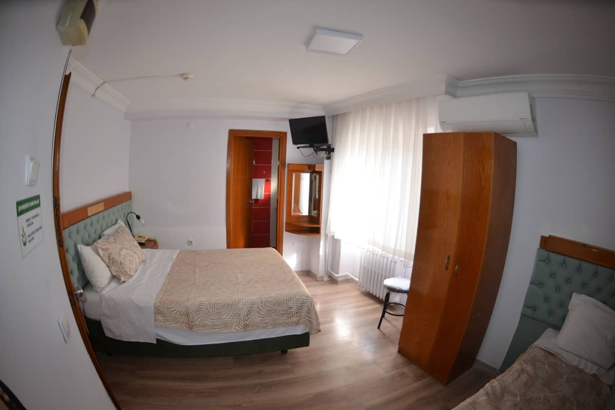 Quarto de hotel com cama, televisão, guarda-roupa e casa de banho.