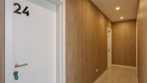 Corredor com paredes de madeira e uma porta branca com o número 24.