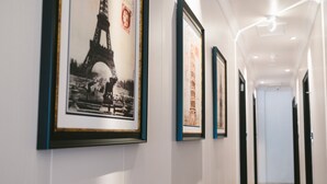 Um corredor com quadros nas paredes, incluindo uma torre famosa e um edifício.