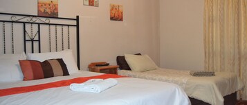 Quarto de hotel com duas camas, uma mesa de cabeceira de madeira e uma pequena mesa com um controle remoto.
