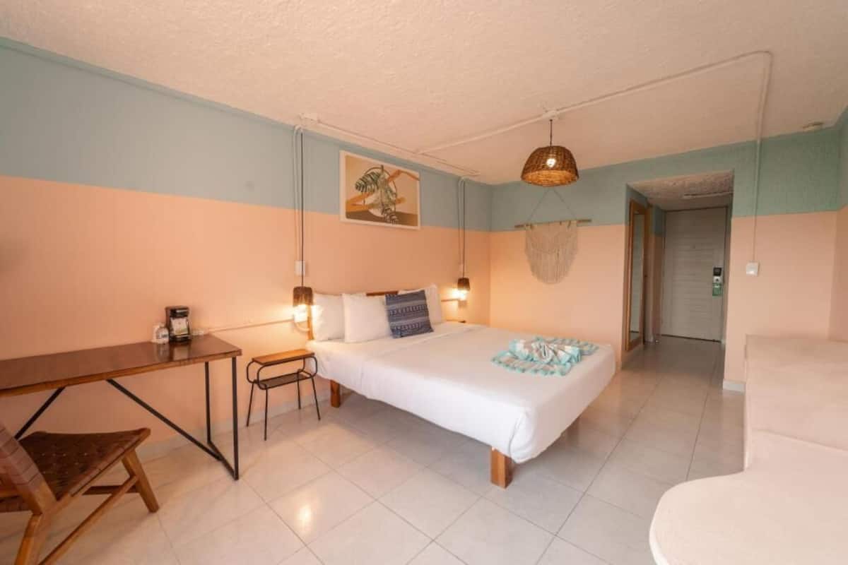 Quarto com cama, mesa de cabeceira, cadeira e escrivaninha.