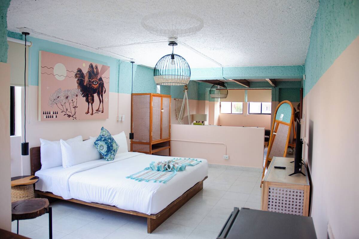 Quarto com cama, escrivaninha, cadeira, espelho e ventilador de teto.