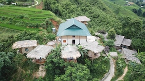 Uma casa tradicional com telhado de palha, rodeada por campos verdejantes em socalcos.