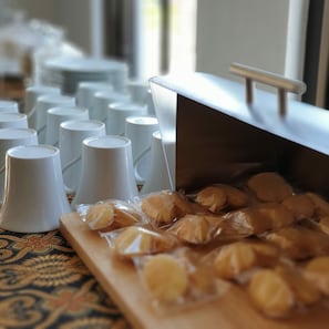 Disposição de buffet com copos de papel brancos e alimentos embalados sobre uma mesa.