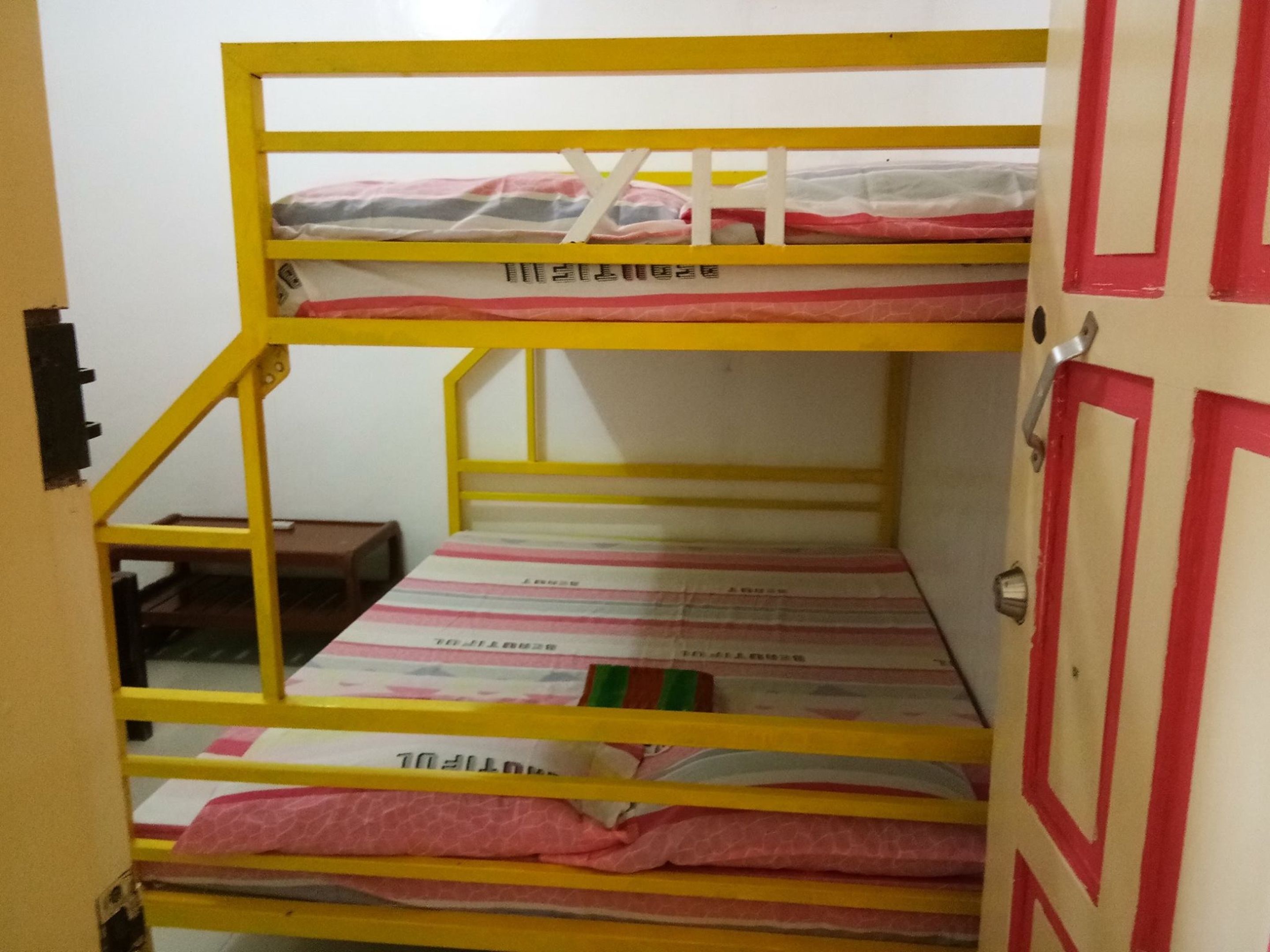 Uma cama beliche com estrutura amarela e porta vermelha.