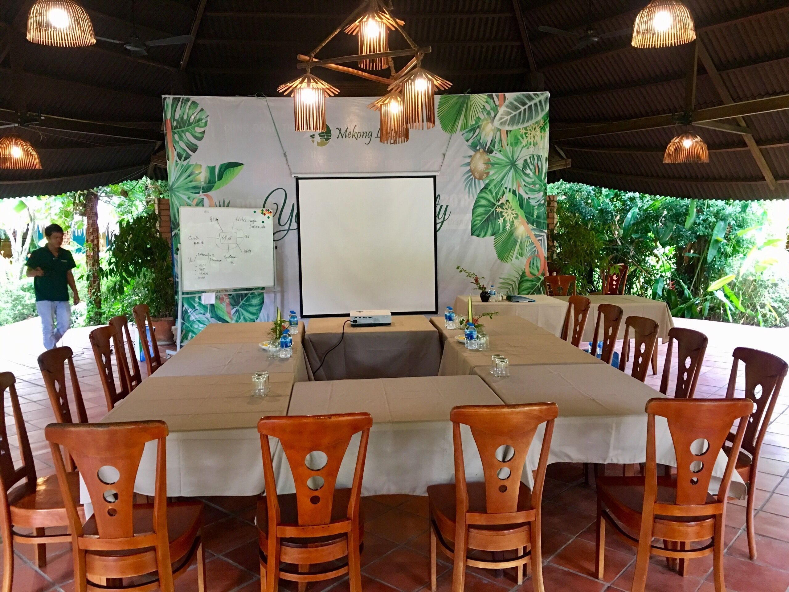 Uma sala de conferências com uma mesa comprida, cadeiras, um quadro branco e uma tela de projetor.