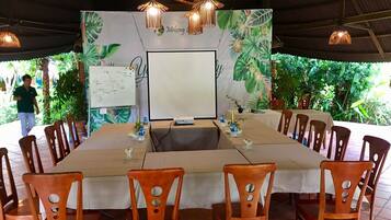 Uma sala de conferências com uma mesa comprida, cadeiras, um quadro branco e uma tela de projetor.