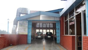 Entrada de hotel com toldo azul e balcão de recepção.