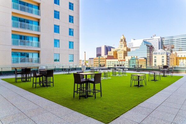 Terraço no telhado com área de estar ao ar livre e o horizonte da cidade ao fundo.