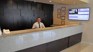 Balcão de recepção de hotel com tela digital exibindo tarifas e comodidades.