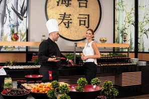 Disposição de buffet com diversos alimentos e uma parede decorativa com caligrafia.