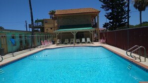 Piscina com espreguiçadeiras e área de estar coberta.