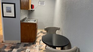 Cozinha compacta com pia, armários de madeira e um pequeno espaço de jantar com uma mesa redonda e duas cadeiras.