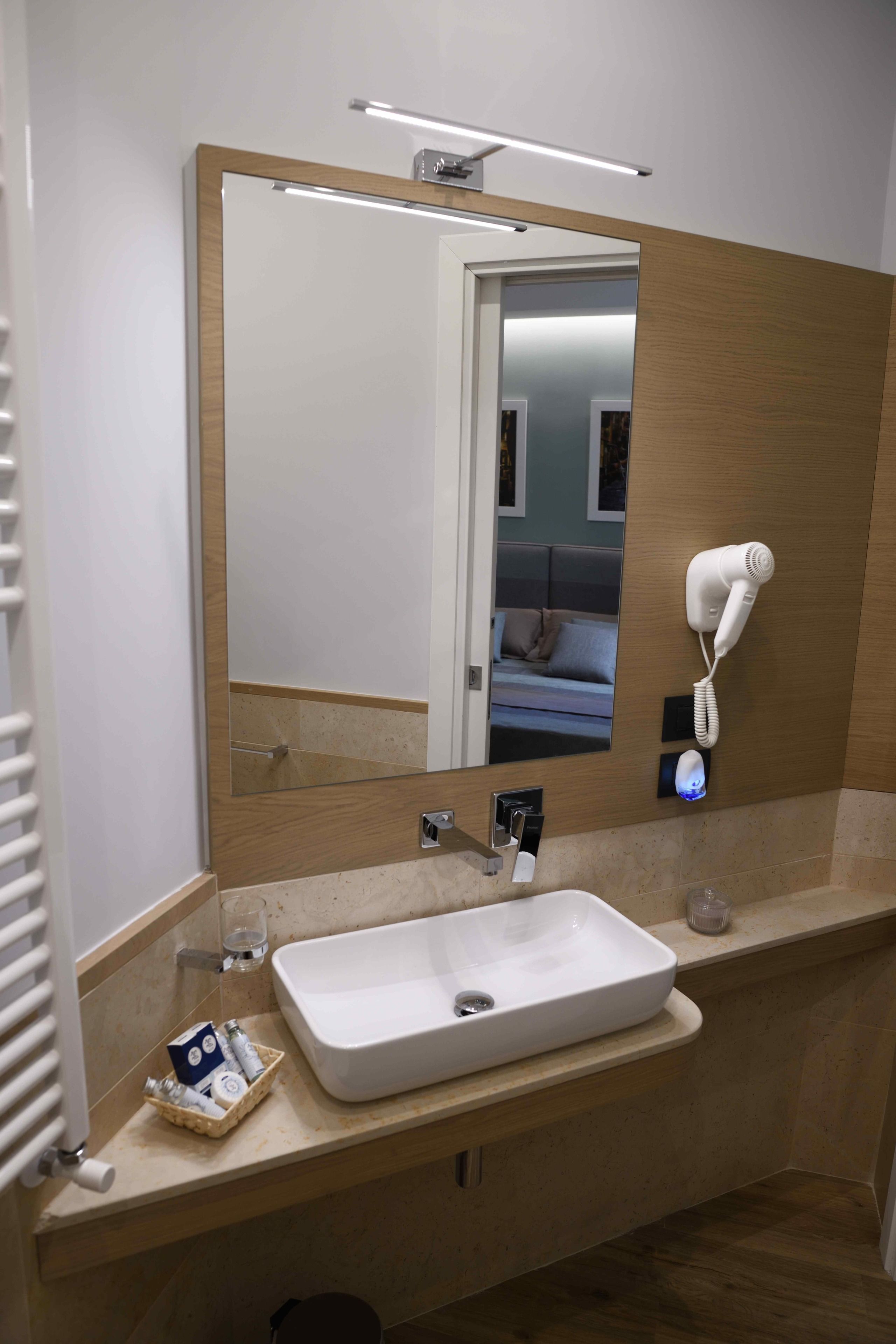 Uma casa de banho moderna com um espelho grande, secador de cabelo e lavatório.