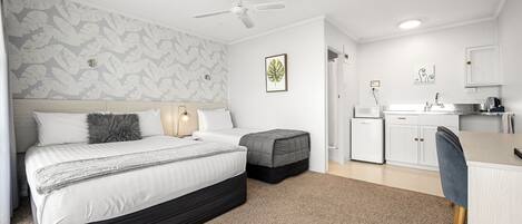 Quarto com cama, mesa de cabeceira e pequena área de trabalho com uma cadeira.