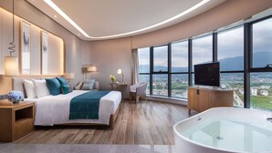 Quarto de hotel moderno com uma cama grande, área de estar, televisão e banheira.