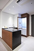 Cozinha moderna com bancada preta, armários de madeira e geladeira embutida.