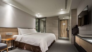 Quarto de hotel moderno com uma cama grande, mesa de cabeceira de madeira, escrivaninha e televisão de tela plana.