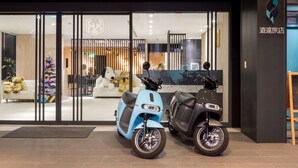 Um interior moderno com duas scooters estacionadas do lado de fora, um pinheiro de Natal e um urso de pelúcia em um sofá.