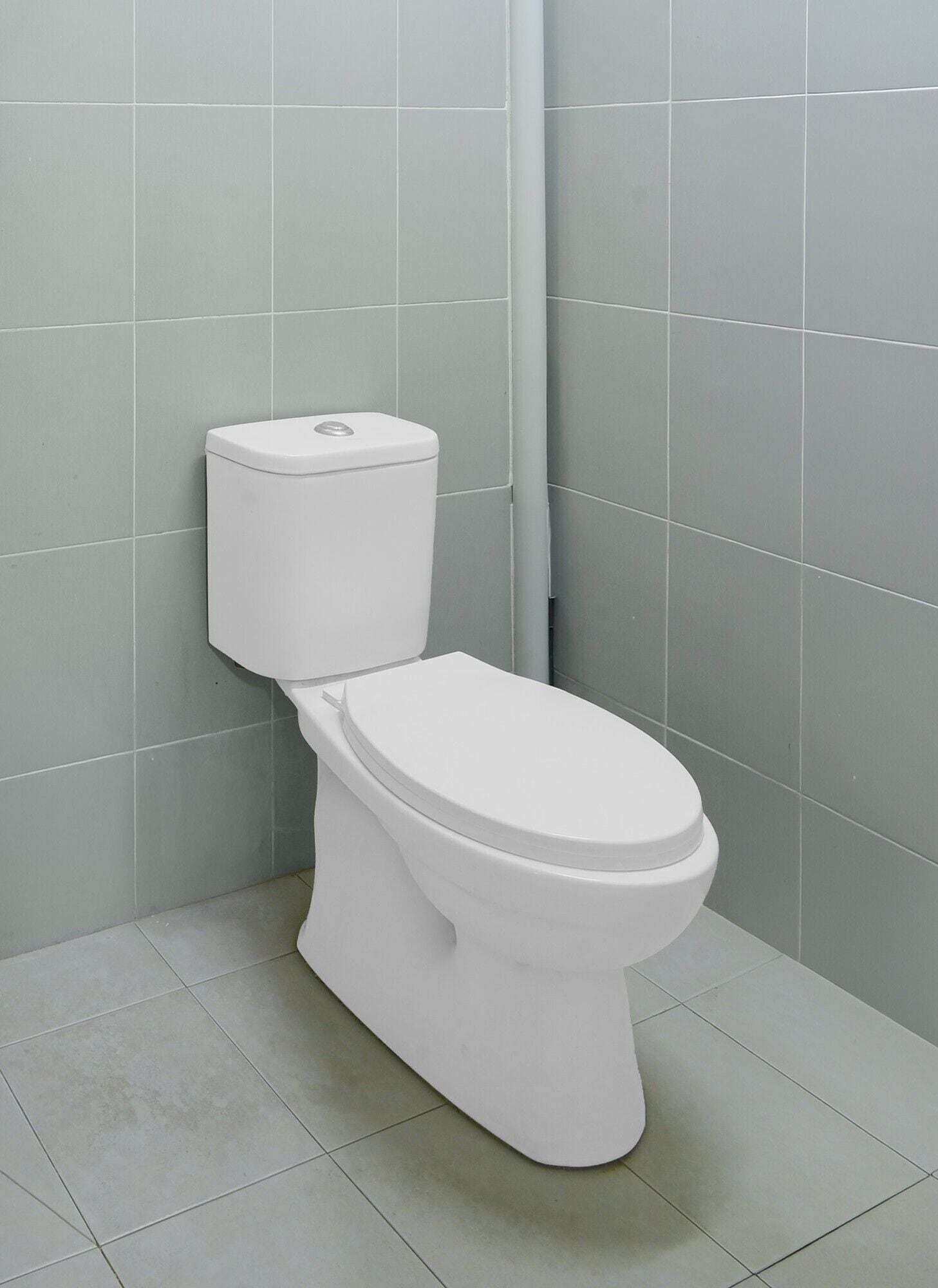 Sanitário branco em banheiro com paredes e chão de azulejos cinzas.