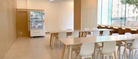 Espaço interior moderno com máquina de vendas automática, divisórias de madeira e vista através de grandes janelas.