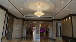 Um hall amplo com um grande candelabro, paredes de mármore e um design moderno no teto.