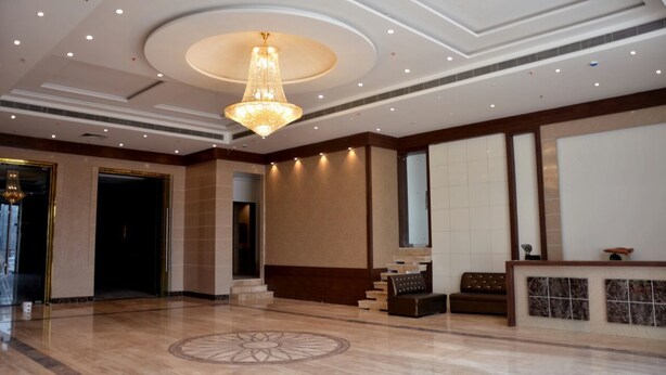 Um hall espaçoso com um lustre imponente, um balcão de recepção e um design de piso estampado.