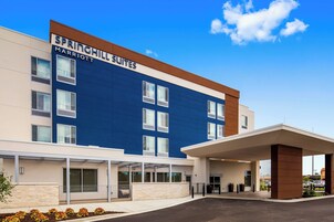 Um hotel moderno com fachada azul, chamado 'Springhill Suites Marriott'. Possui entrada coberta, fachada de pedra e área de estacionamento.