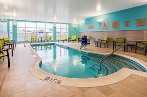 Uma área de piscina com cadeiras, elevador de piscina e placas de segurança.