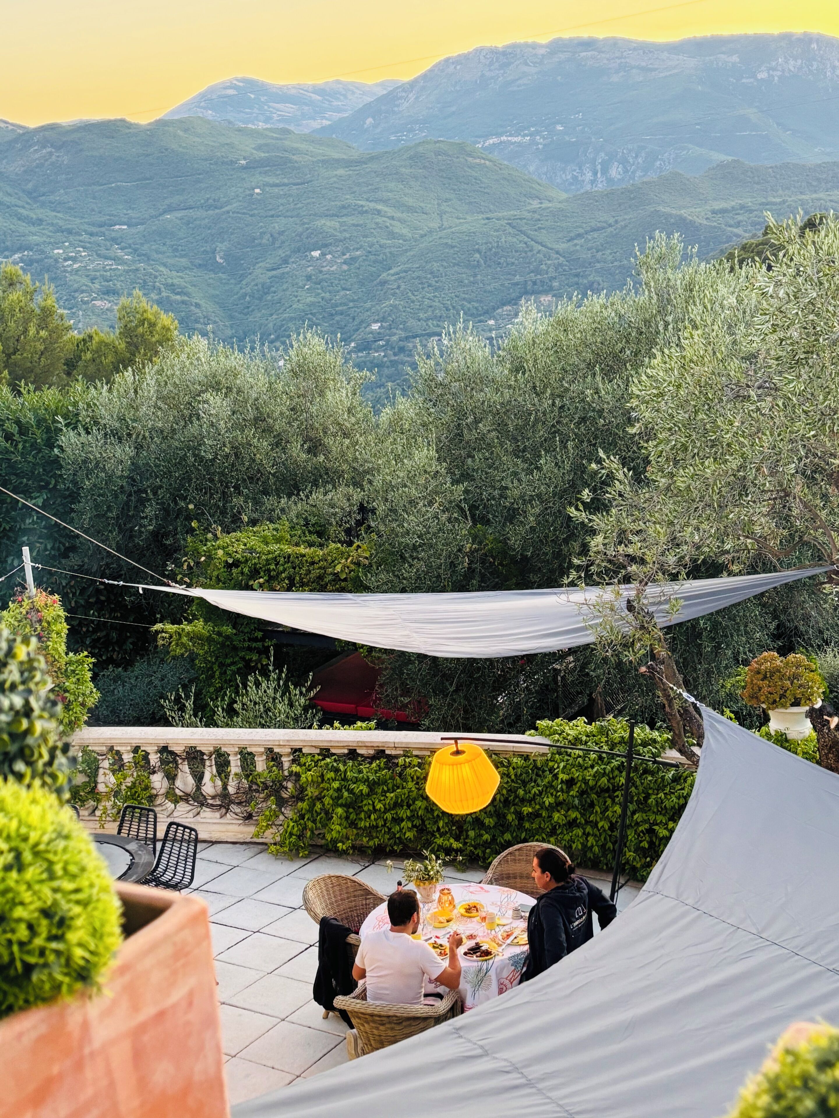 Uma área de refeições ao ar livre com vista para montanhas, uma mesa com comida e um toldo.