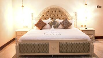 Uma cama grande com cabeceira estofada, duas mesas de cabeceira e um tapete decorativo.