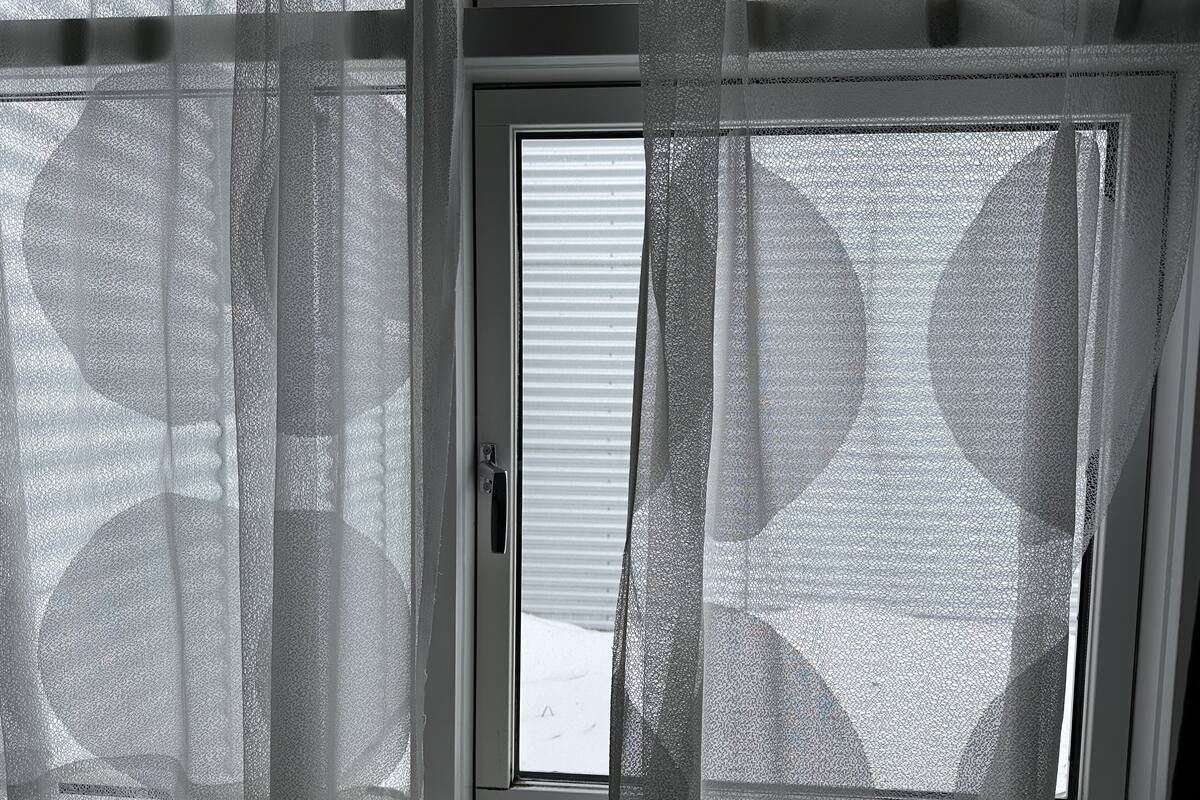 Janela com cortinas leves e porta deslizante fechada.