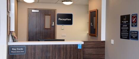 Bancada de recepção com uma placa indicando 'Reception' e uma placa com 'Key Cards' abaixo.