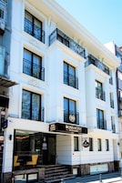 Um hotel de vários andares com um grande letreiro chamativo "Boss Hotel", janelas amplas e estilo arquitetônico clássico.