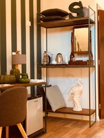 Quarto com beliche, escrivaninha com abajur, cafeteira, bule e um flamingue decorativo.