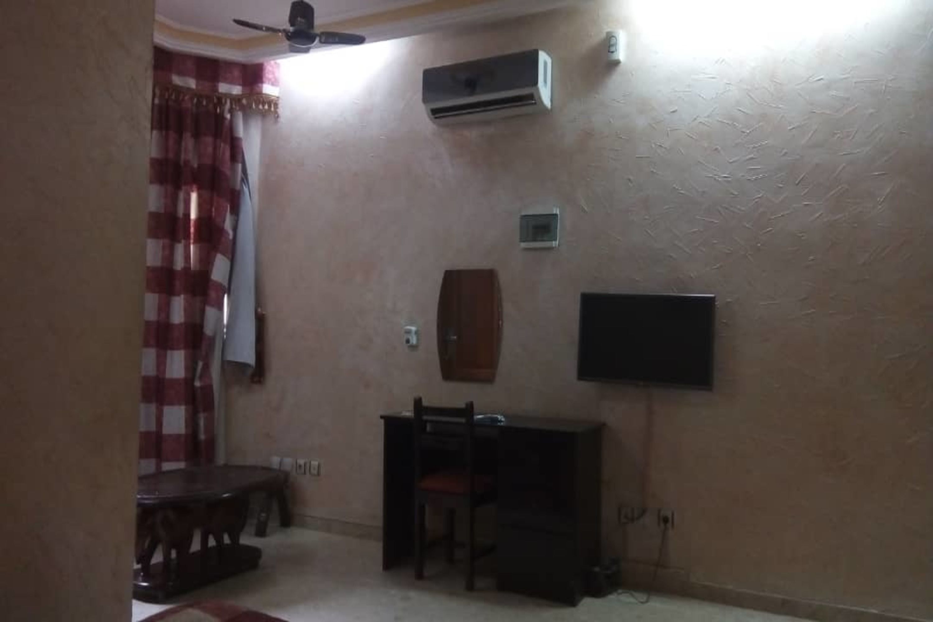 Quarto com escrivaninha, cadeira e televisão de tela plana na parede.