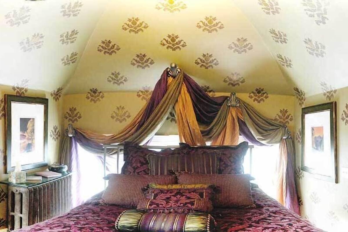 Quarto com cama de dossel, papel de parede estampado e radiador.