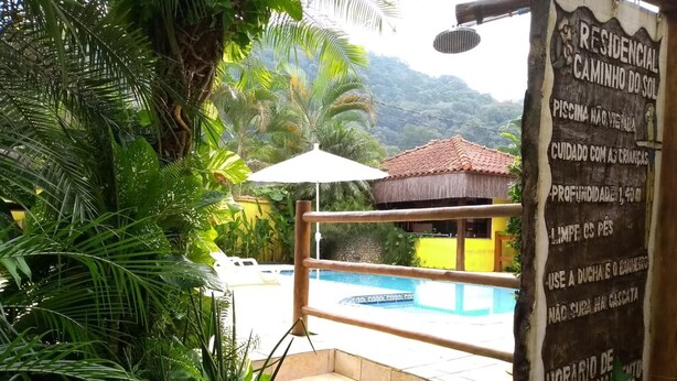 Uma área de piscina com escadas que levam a um edifício, cercada por vegetação exuberante.