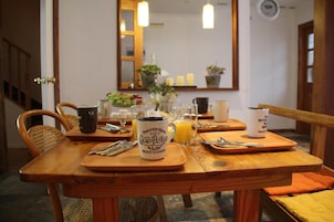 Uma mesa de jantar de madeira com talheres, uma caneca e um copo de sumo de laranja.
