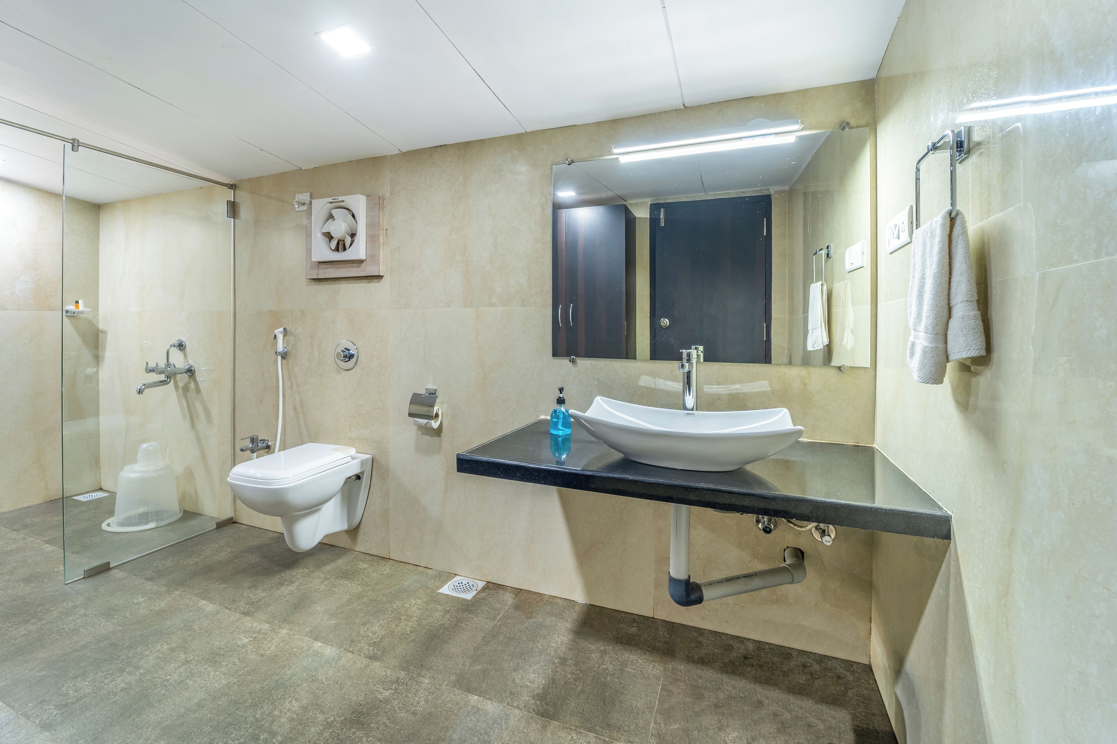 Uma casa de banho moderna com cabine de duche em vidro, sanita branca, lavatório com espelho e um porta-toalhas.