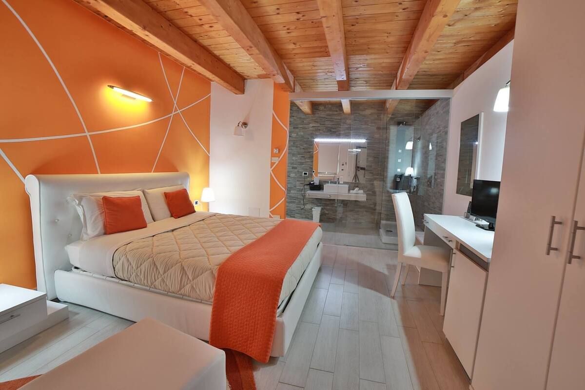 Quarto com cama, mesa de cabeceira e escrivaninha com cadeira.