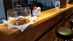 Um balcão de madeira com uma cúpula de vidro que contém biscoitos e uma pequena tigela de maçãs.